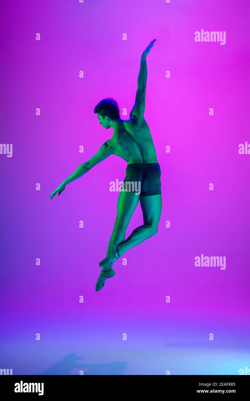 Power. Young and graceful ballet dancer on purple studio background in ...