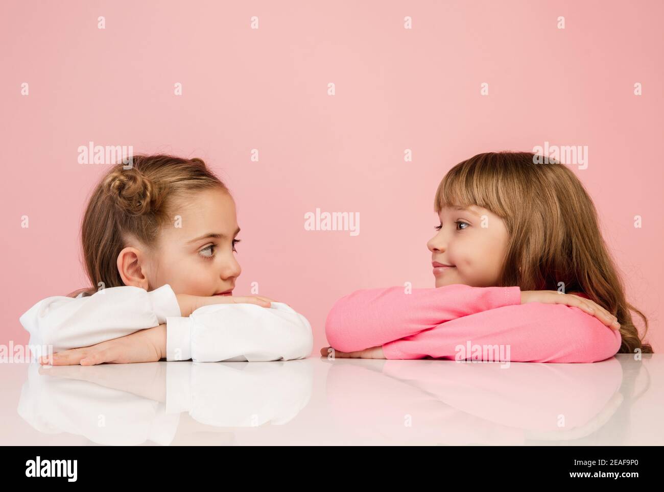 Kindly. Happy kids, girls isolated on coral pink studio background ...