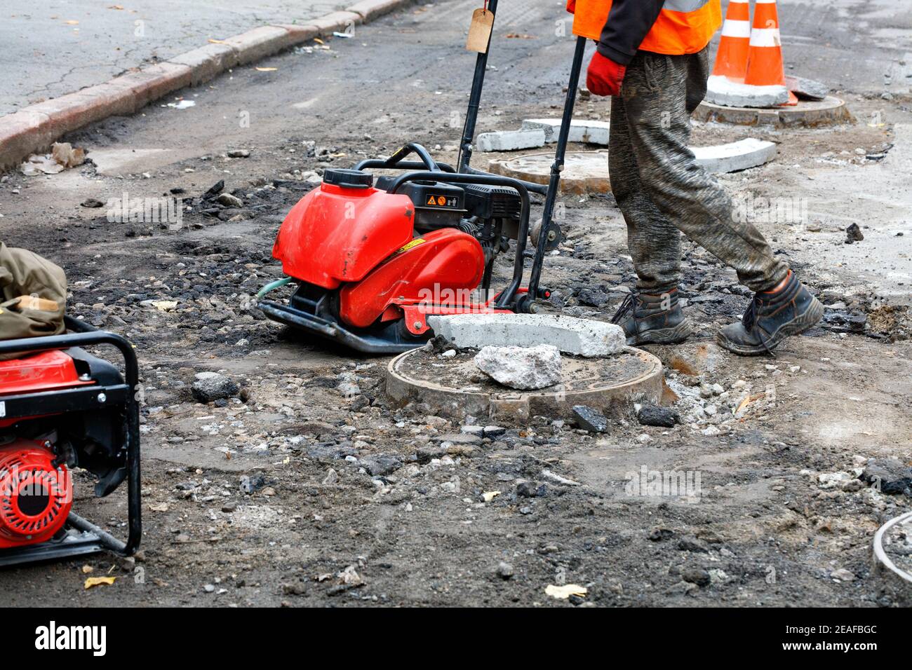 A road worker repairs and installs sewers on the road using a compactor ...