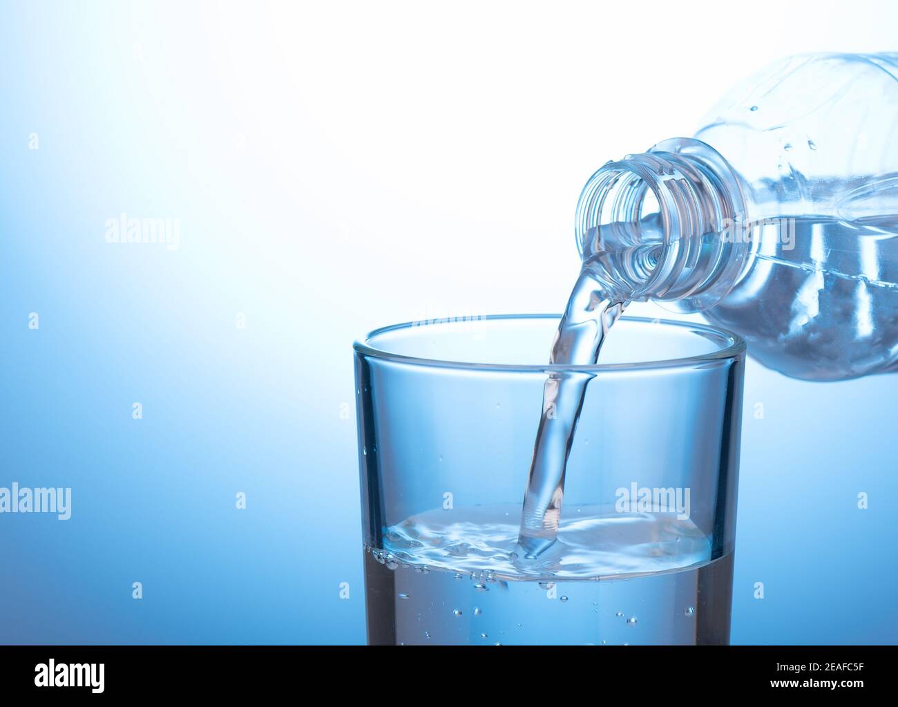 Pouring water from a plastic bottle into a glass beaker. Close up Stock ...