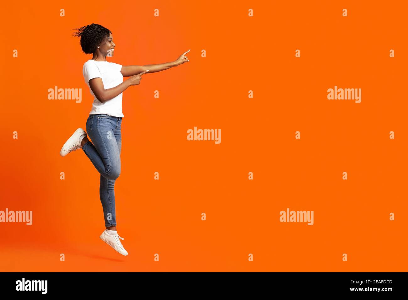 Happy young black woman jumping up and showing copy space Stock Photo ...