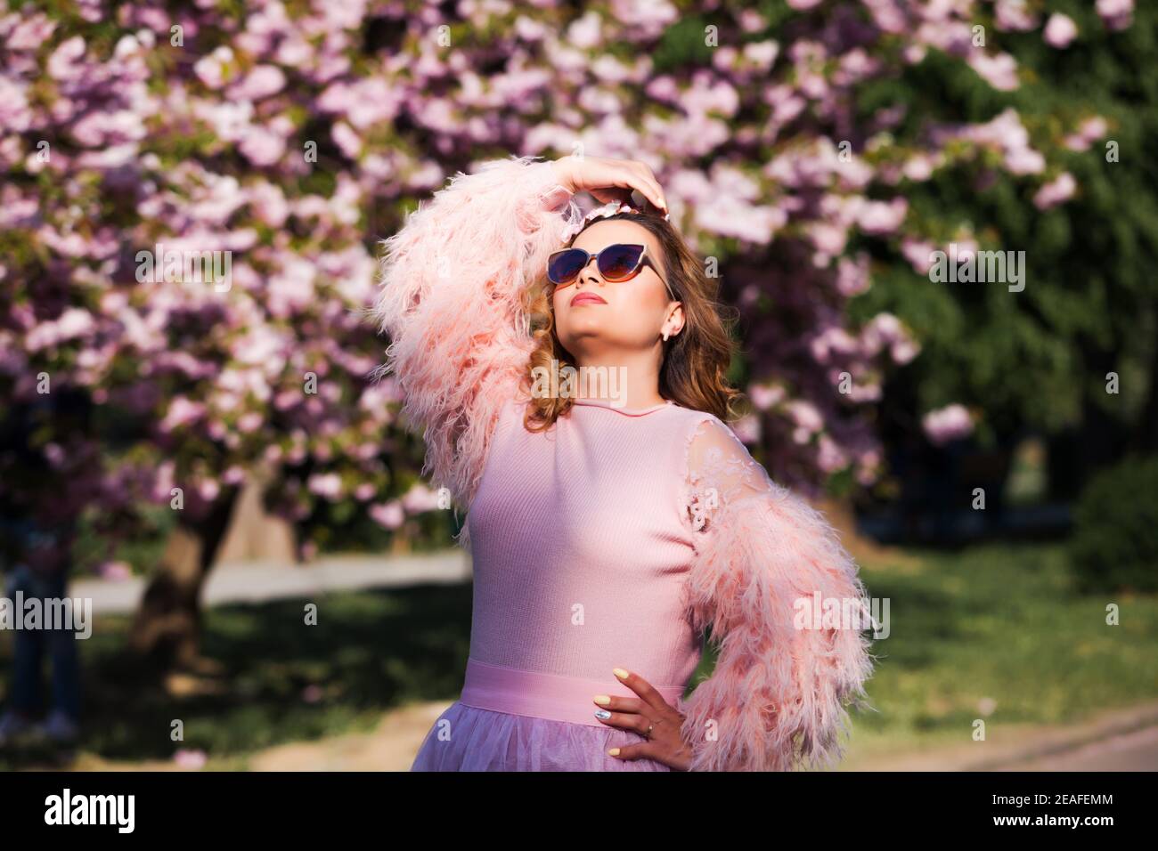 the girl is standing under the pink tree that bloom Stock Photo - Alamy