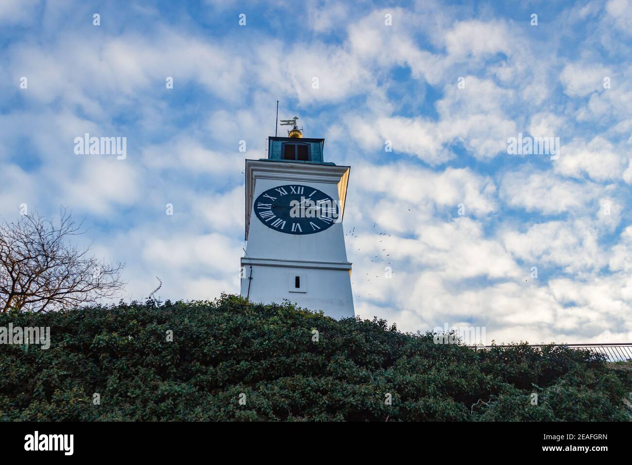 Low angle shot of a white tower with a big wall clock and sky with ...