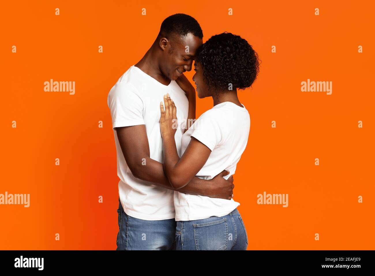 African american couple in love hugging on orange Stock Photo - Alamy