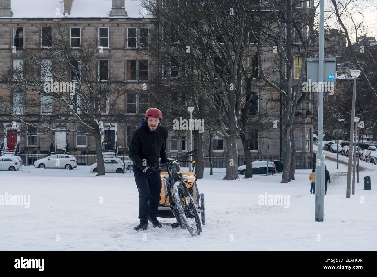 A man pushing a bike with a trailer for a child through snow Stock ...