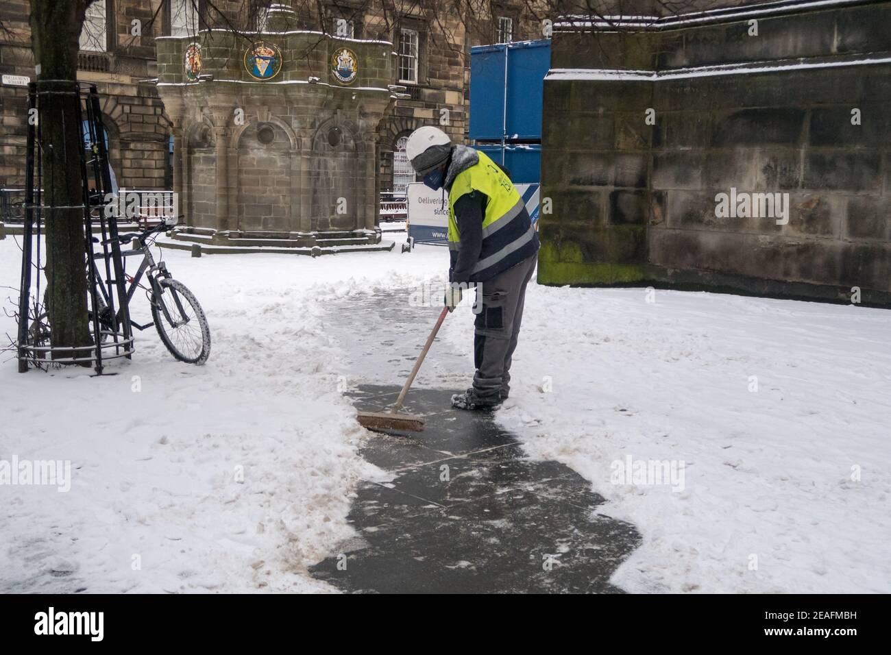 A workman clearing a path from snow using a shovel Stock Photo - Alamy