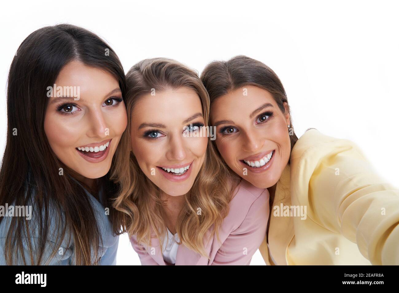 Three women in pastel suits posing over white background Stock Photo ...