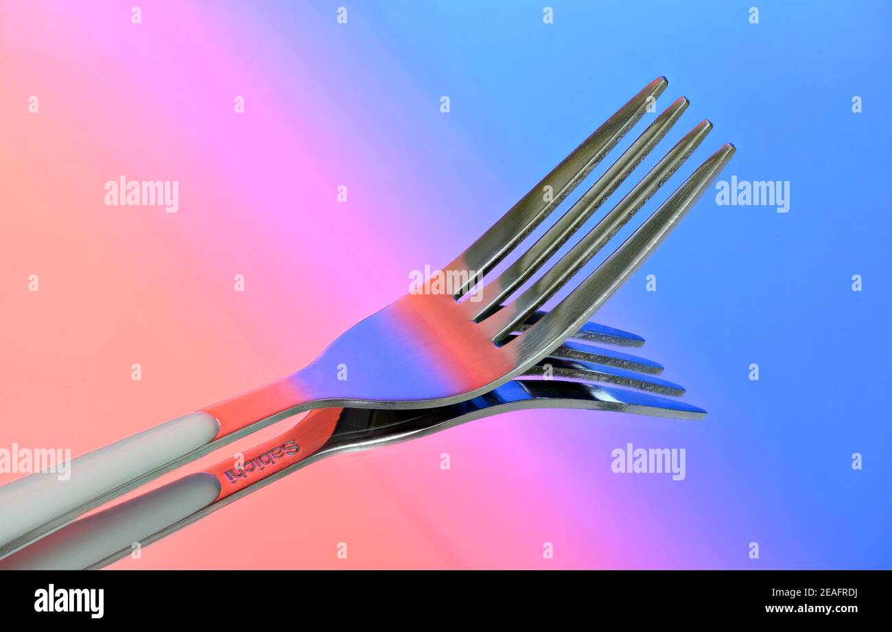 Stainless steel kitchen fork on a reflective surface photographed under ...