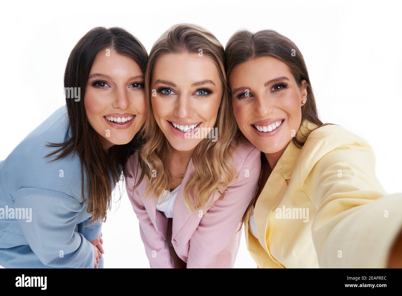 Three women in pastel suits posing over white background Stock Photo ...