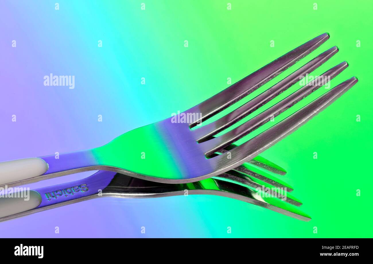 Stainless steel kitchen fork on a reflective surface photographed under ...