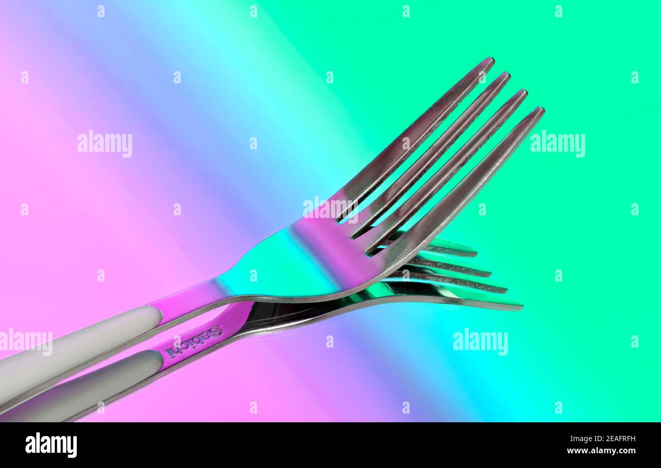 Stainless steel kitchen fork on a reflective surface photographed under ...