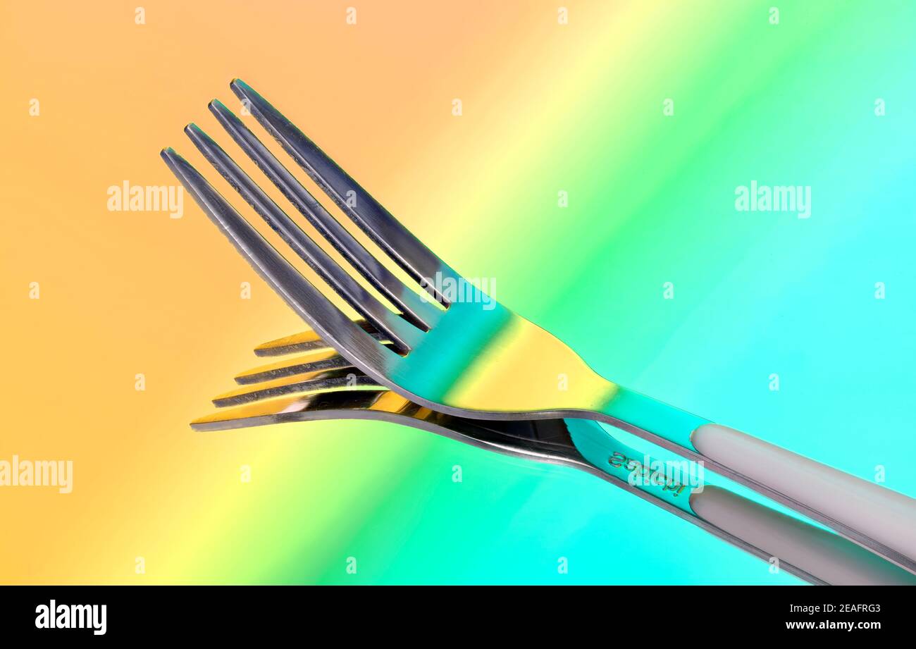 Stainless steel kitchen fork on a reflective surface photographed under ...