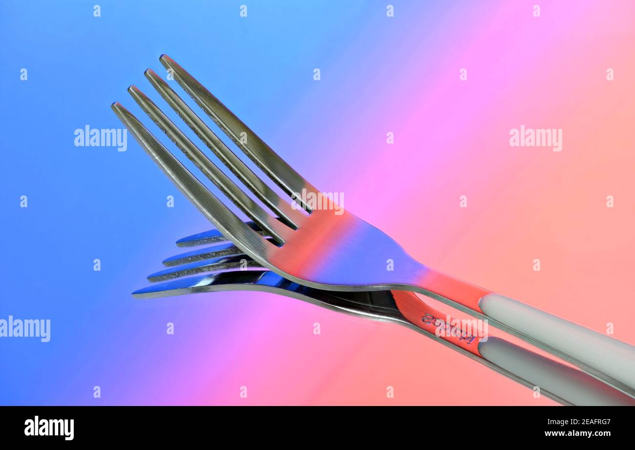 Stainless steel kitchen fork on a reflective surface photographed under ...
