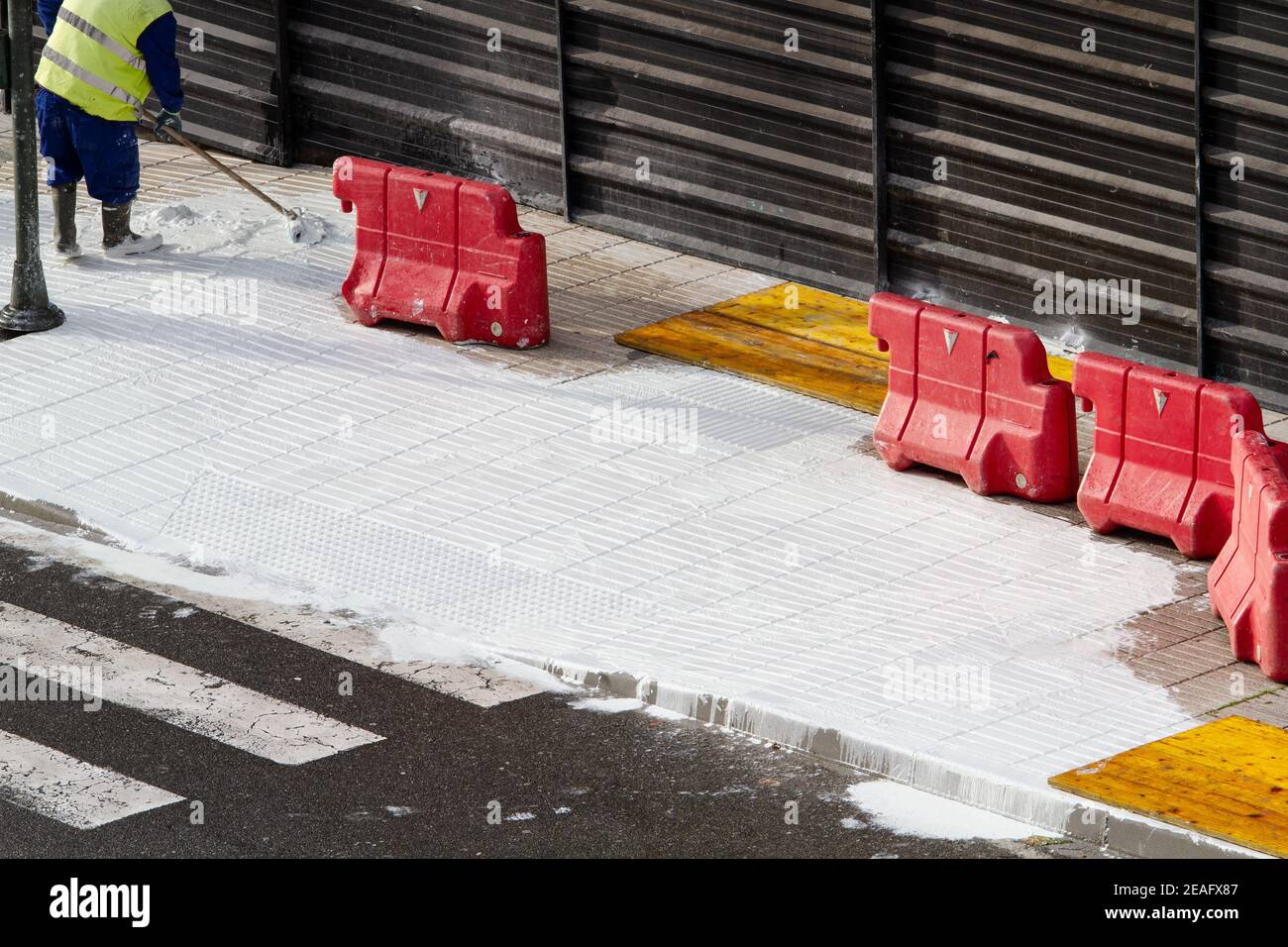 Construction worker working with white concrete on a sidewalk under ...