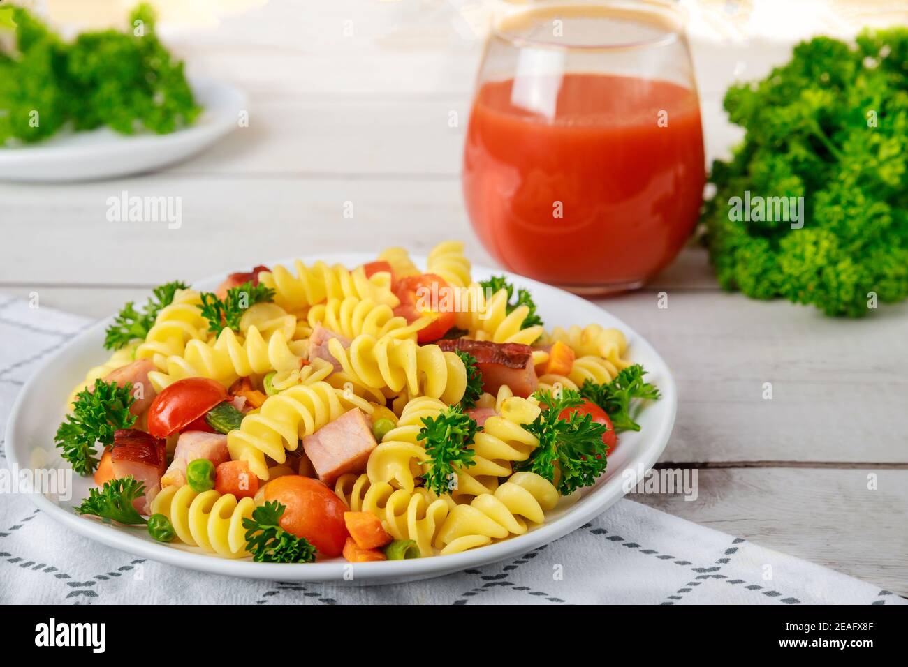 Italian pasta, ham and vegetables with glass of tomato juice. Balanced ...