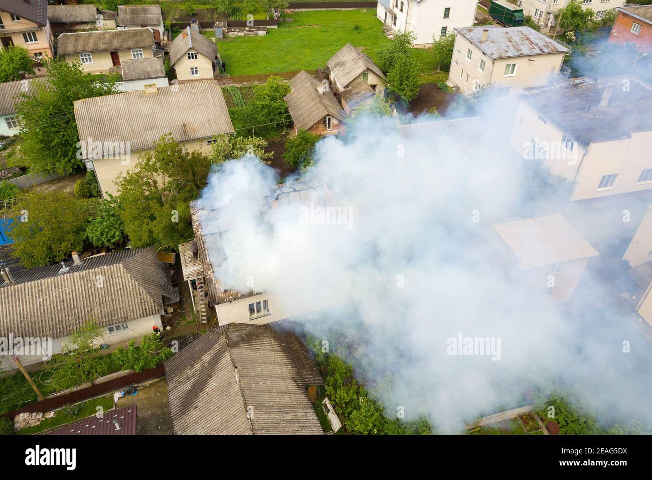 Aerial view of a house on fire with orange flames and white thick smoke ...