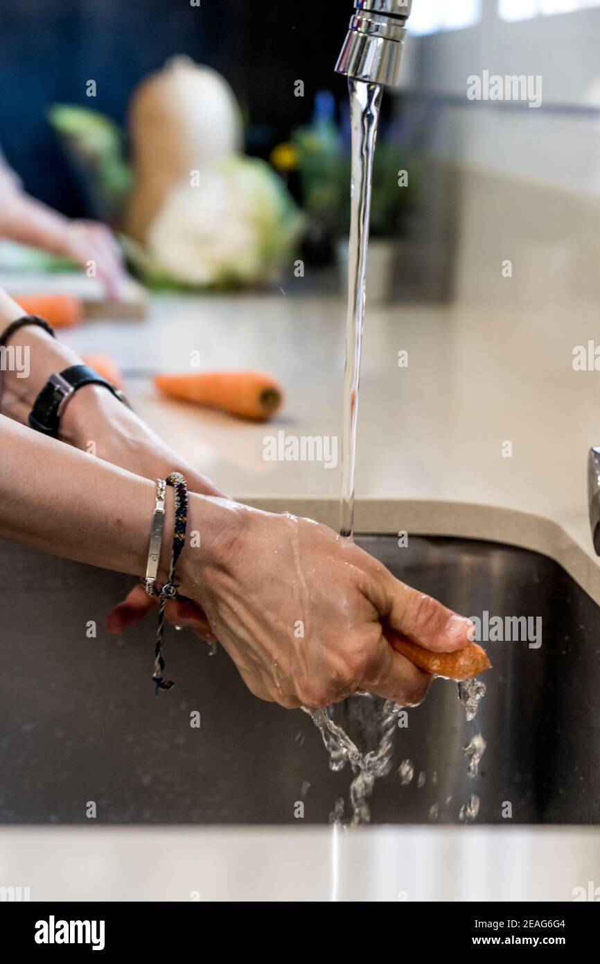 Vertical shot of a female washing carrot in the kitchen sink Stock ...