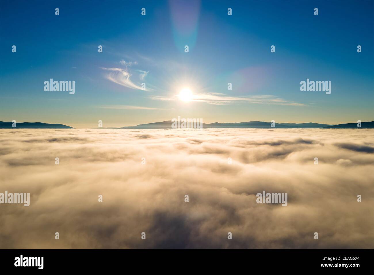 Aerial view of vibrant sunset over white dense clouds with distant dark ...
