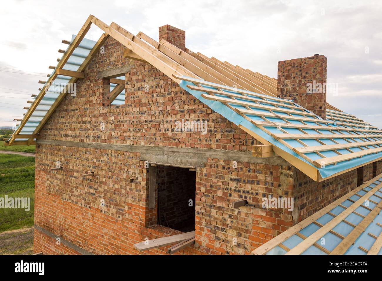 Aerial view of a brick house with wooden roof frame under construction ...