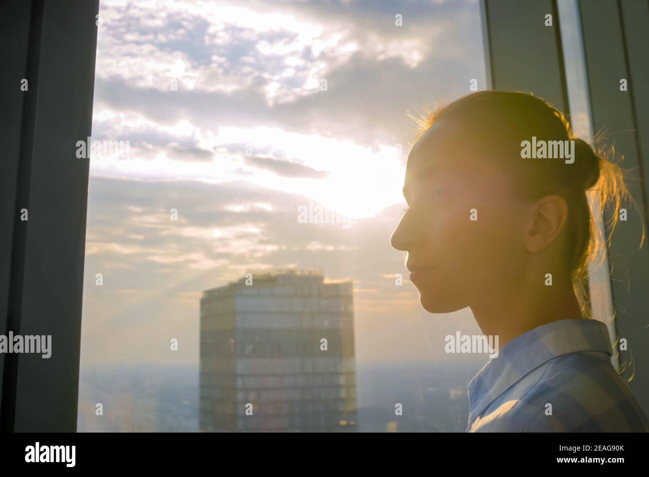 Woman looking at cityscape through window of skyscraper - sun lens ...