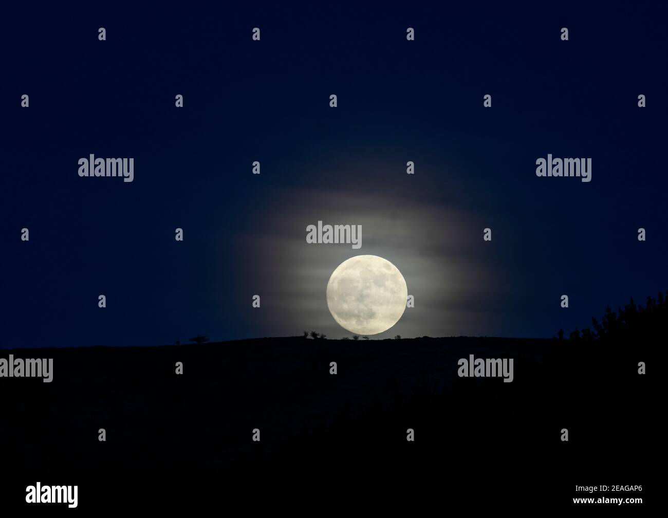 Full moon rising behind the mountain Stock Photo - Alamy
