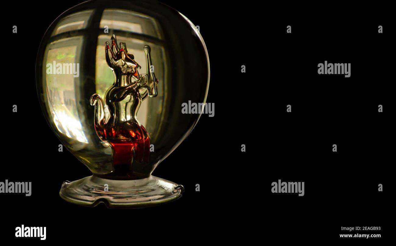 A bottle with a glass figure of a devil with red elements inside ...