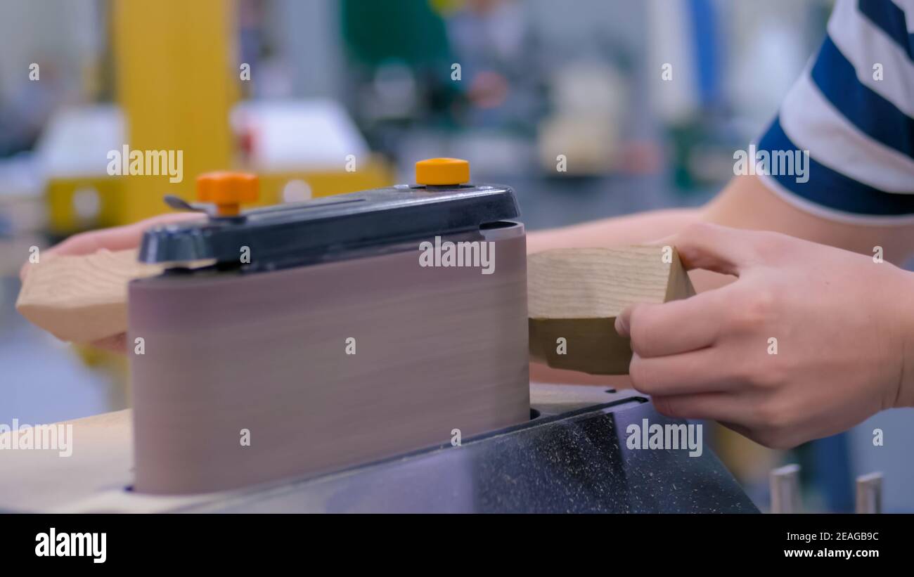 Man carpenter using belt sander machine, polishing wood product: close ...