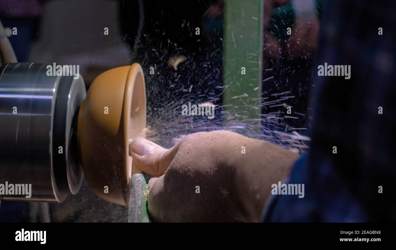 Carpenter using chisel for shaping wood piece on lathe - side view ...