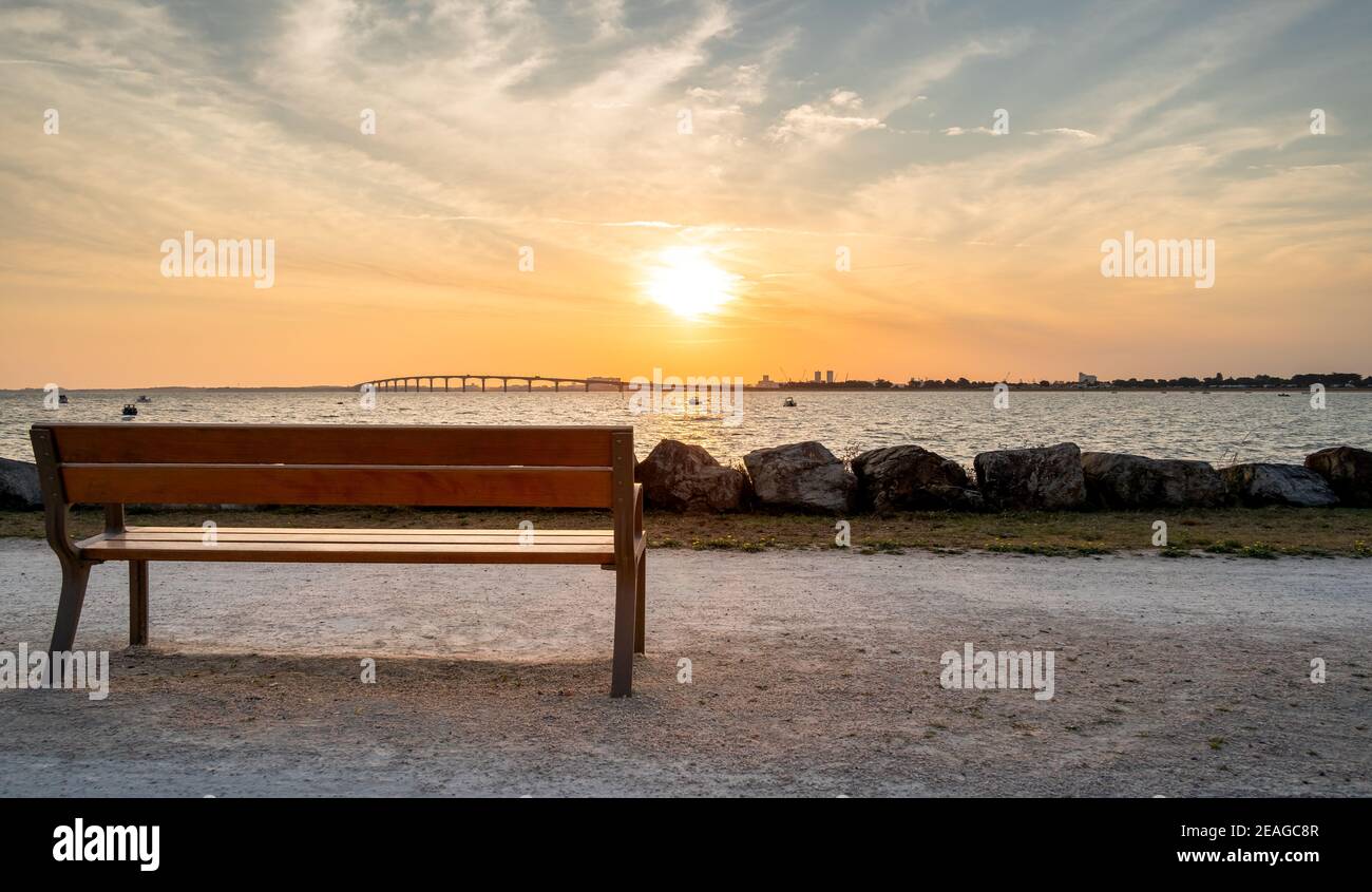 Isolated public bench at sunrise. Re island bridge in the background ...