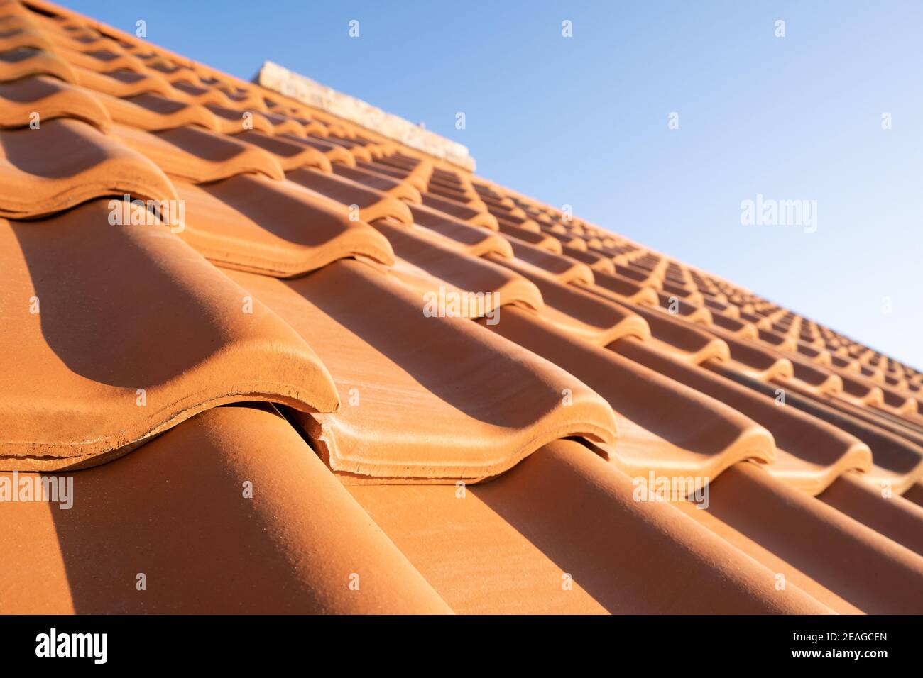 Overlapping rows of yellow ceramic roofing tiles covering residential ...