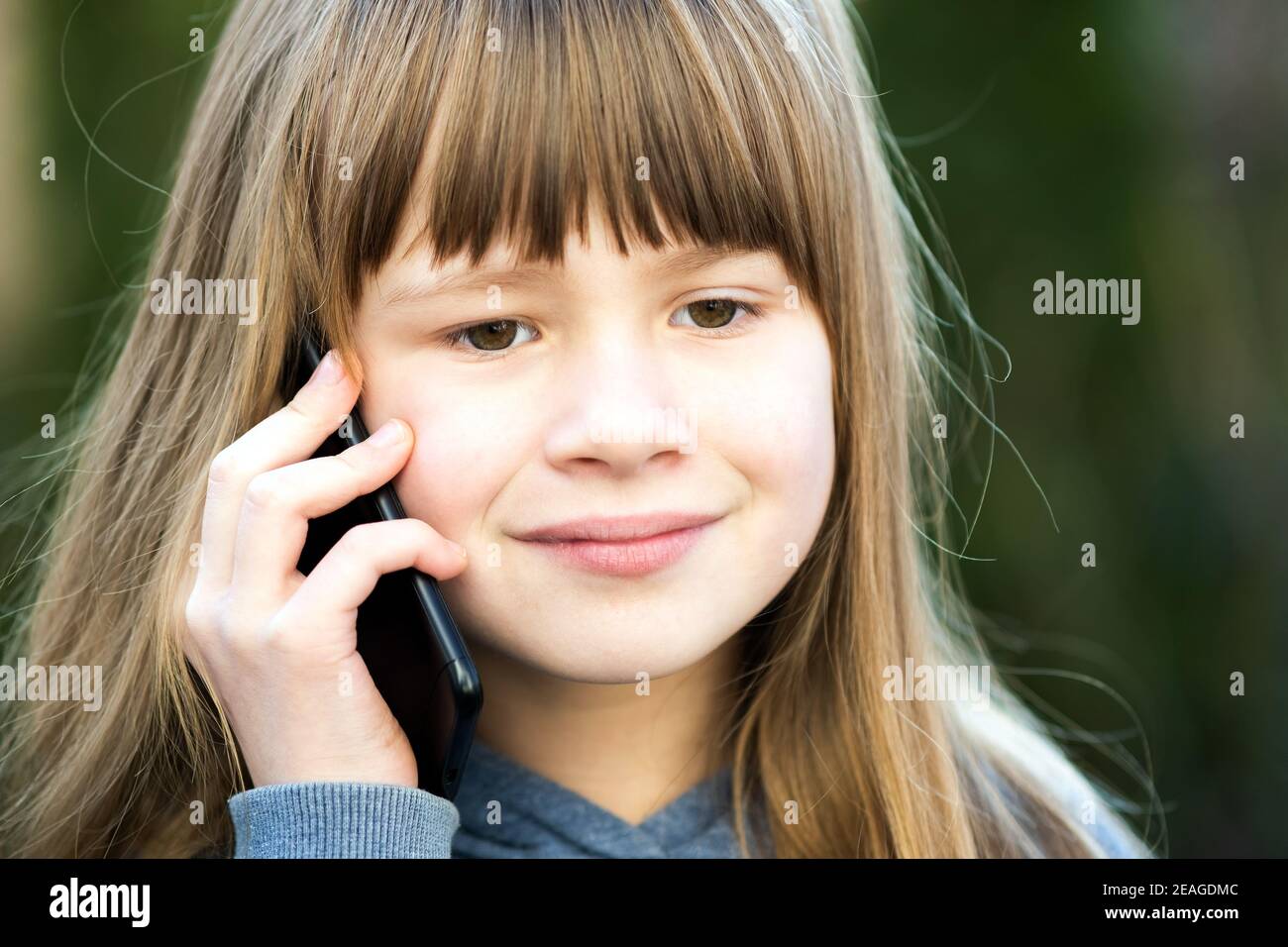 Portrait of pretty child girl with long hair talking on cell phone ...