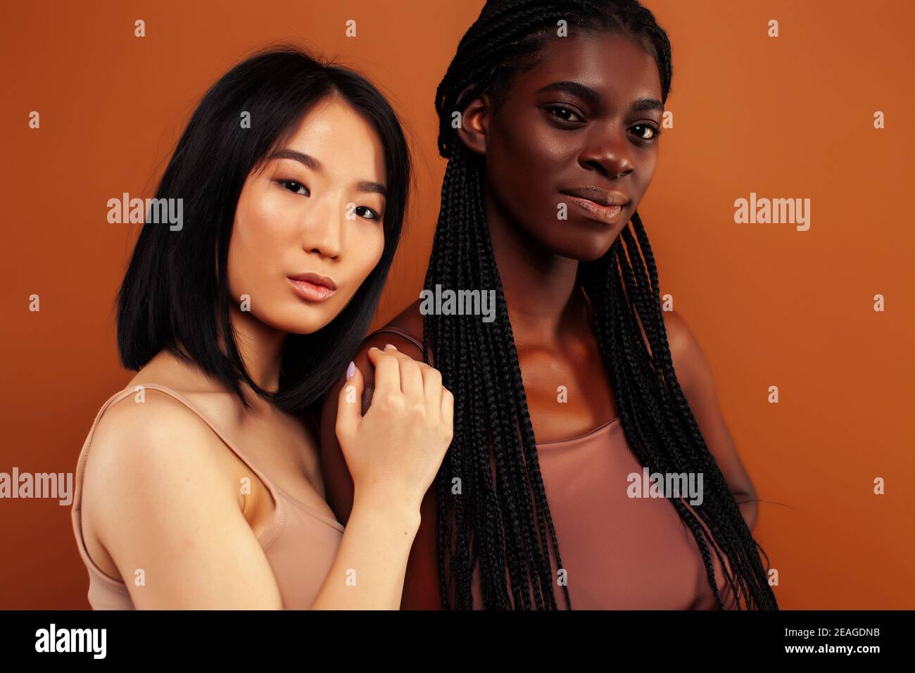 young pretty asian and afro woman posing cheerful together on brown ...