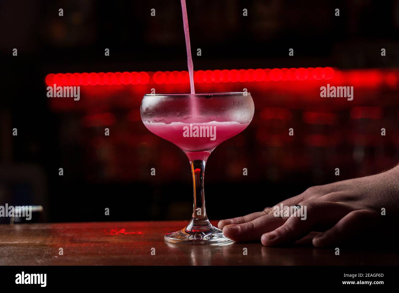 Classic Pink Lady cocktail closeup with flower and cherry on bar ...