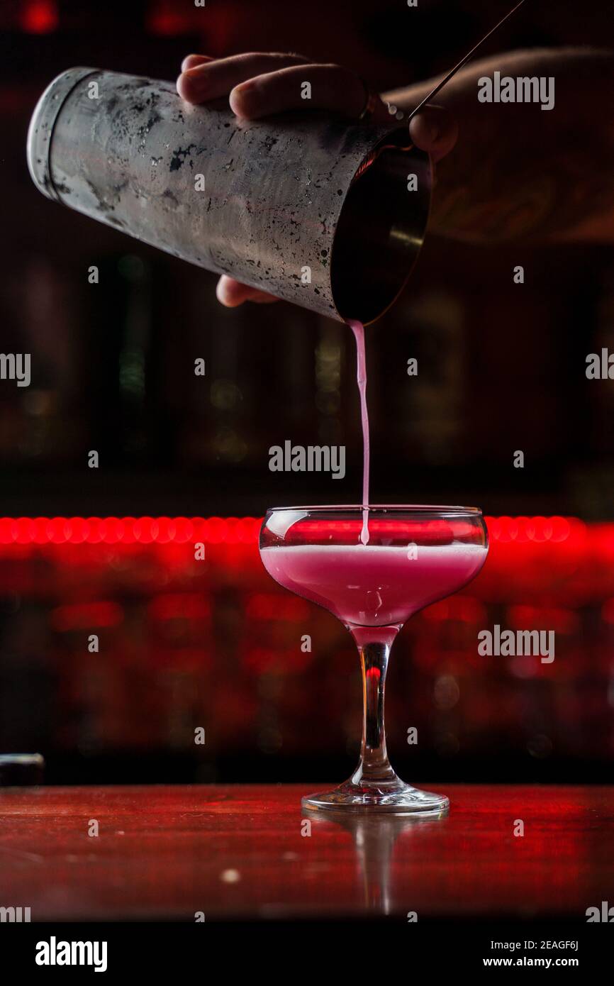 Classic Pink Lady cocktail closeup with flower and cherry on bar ...