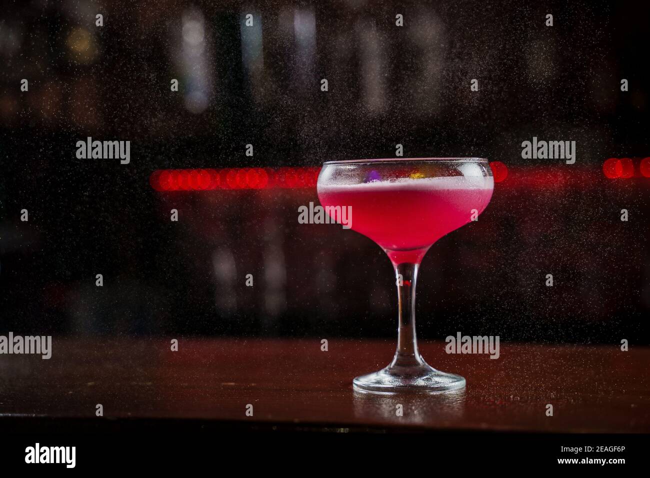 Classic Pink Lady cocktail closeup with flower and cherry on bar ...