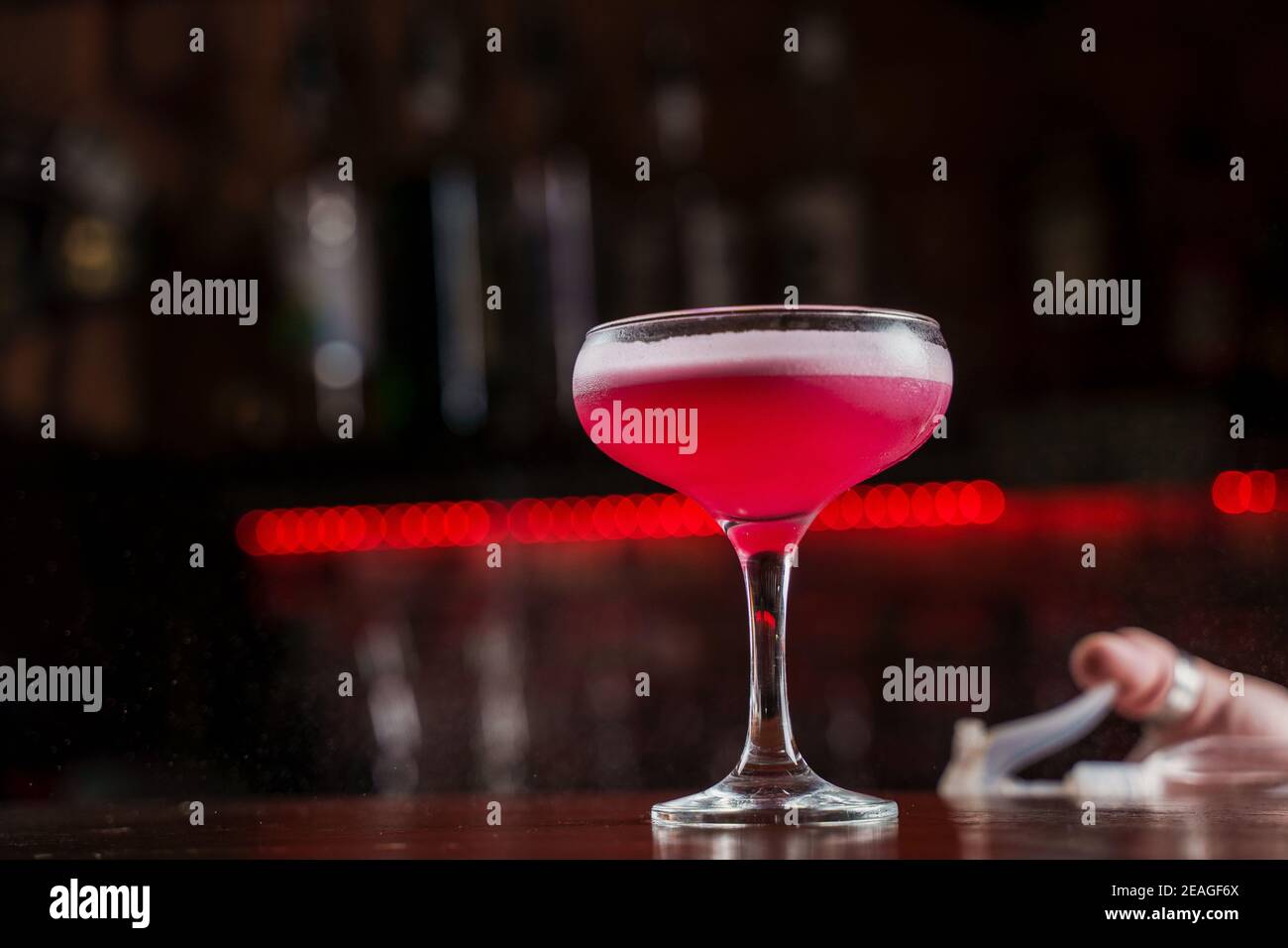 Classic Pink Lady cocktail closeup with flower and cherry on bar ...