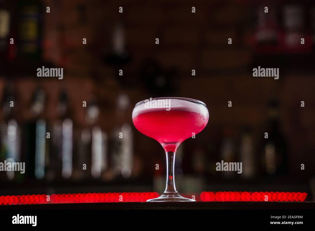 Classic Pink Lady cocktail closeup with flower and cherry on bar ...