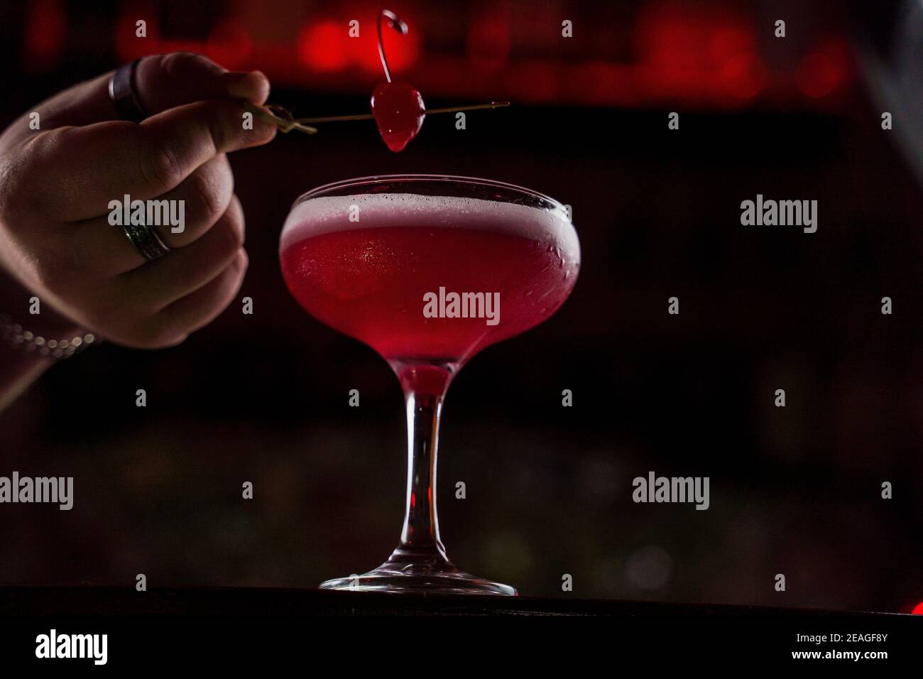Classic Pink Lady cocktail closeup with flower and cherry on bar ...