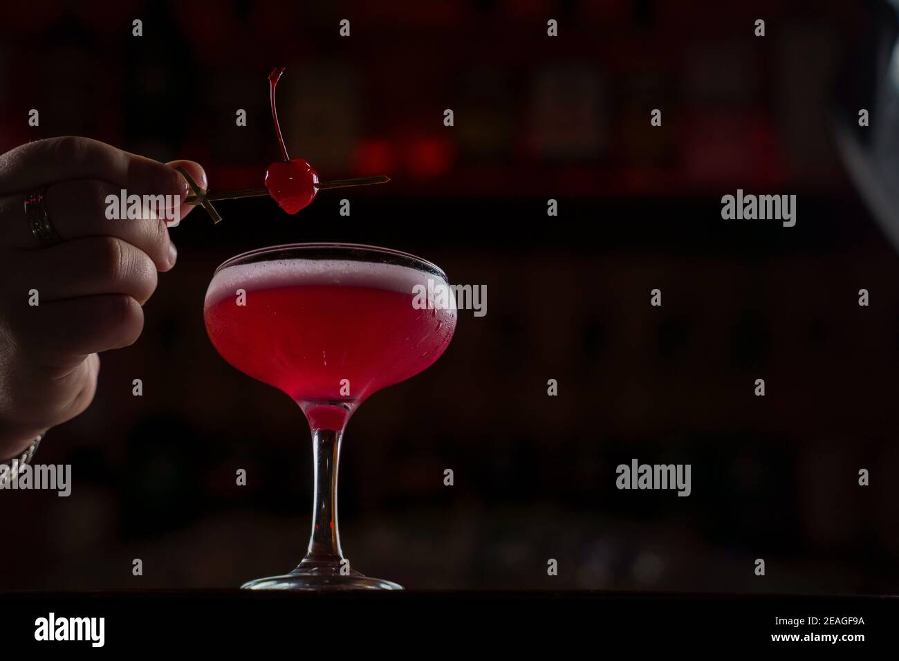 Classic Pink Lady cocktail closeup with flower and cherry on bar ...