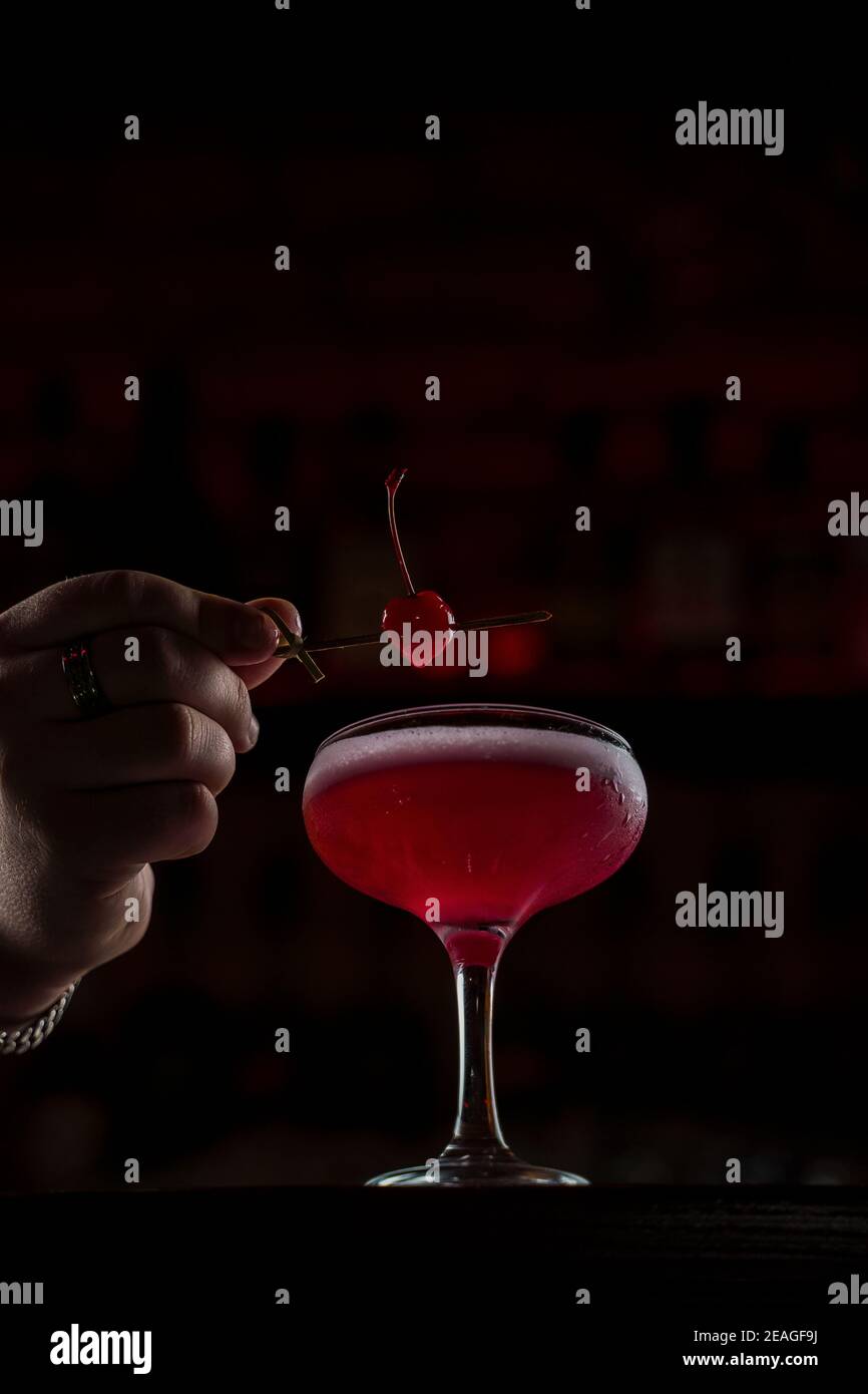 Classic Pink Lady cocktail closeup with flower and cherry on bar ...