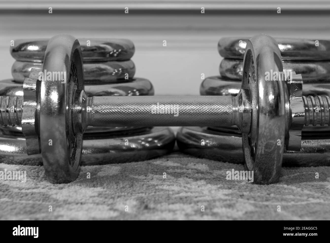 Black and white photo of a small dumbbell on the floor with two stacks ...