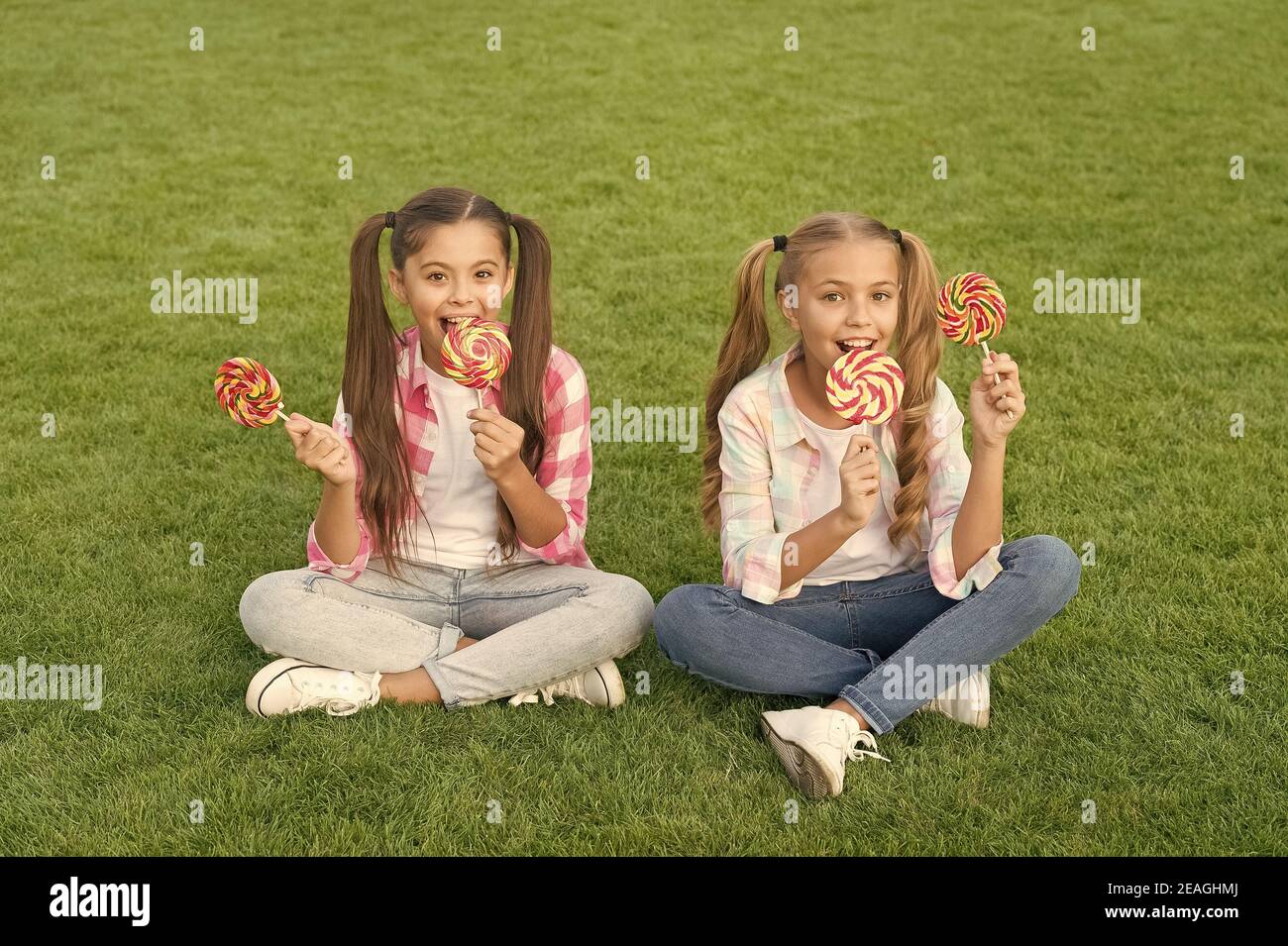 Sweet caramel. Happy children hold candy sit grass. Candy shop ...