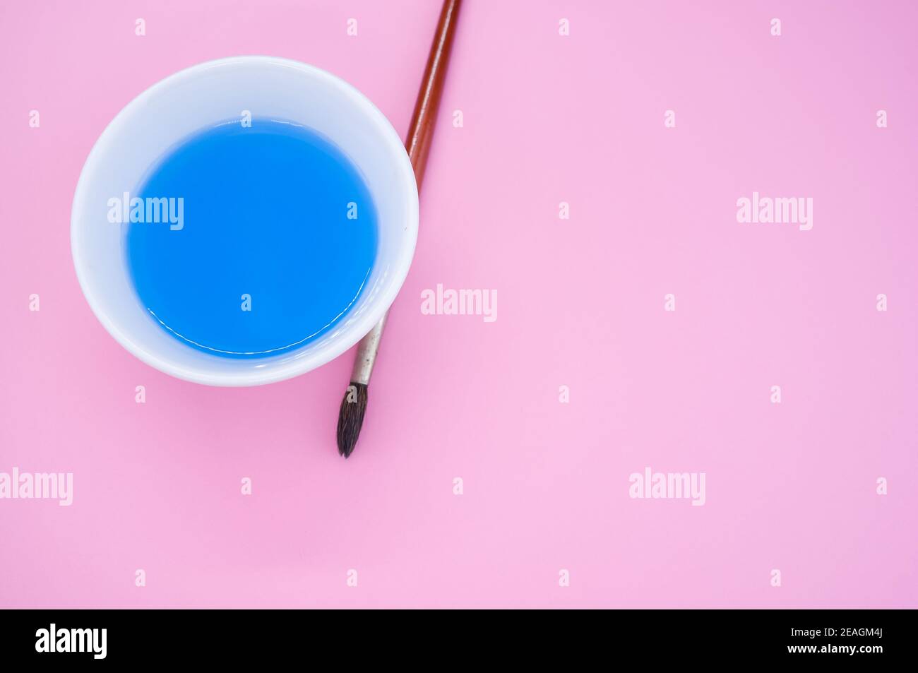 Top view of blue liquid watercolor paint on a bowl and paintbrush ...