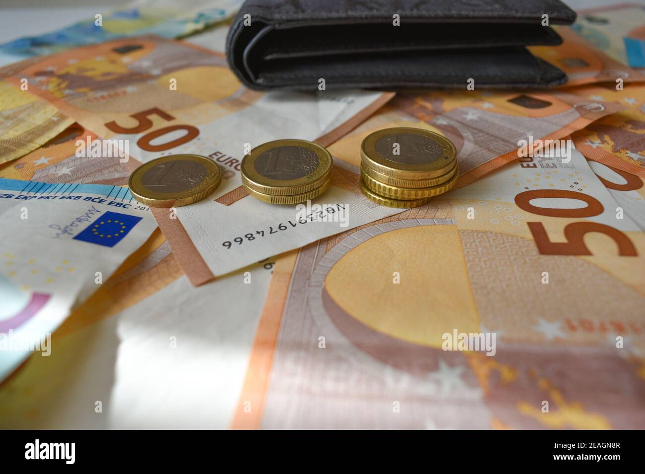 Closeup of Euro banknotes on each other with stacked coins and a black ...