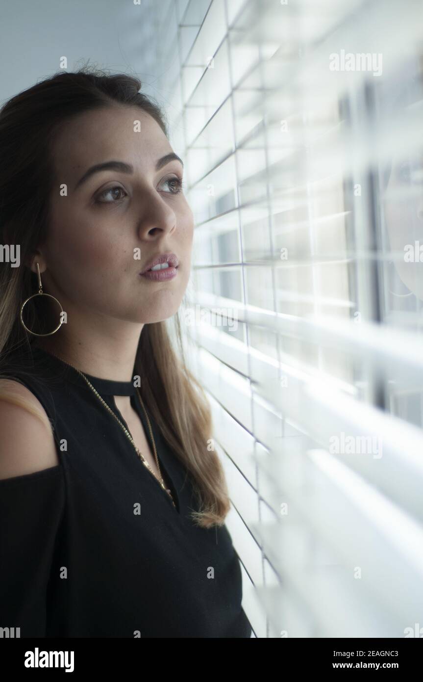 Professional Hispanic young woman looking something through window ...