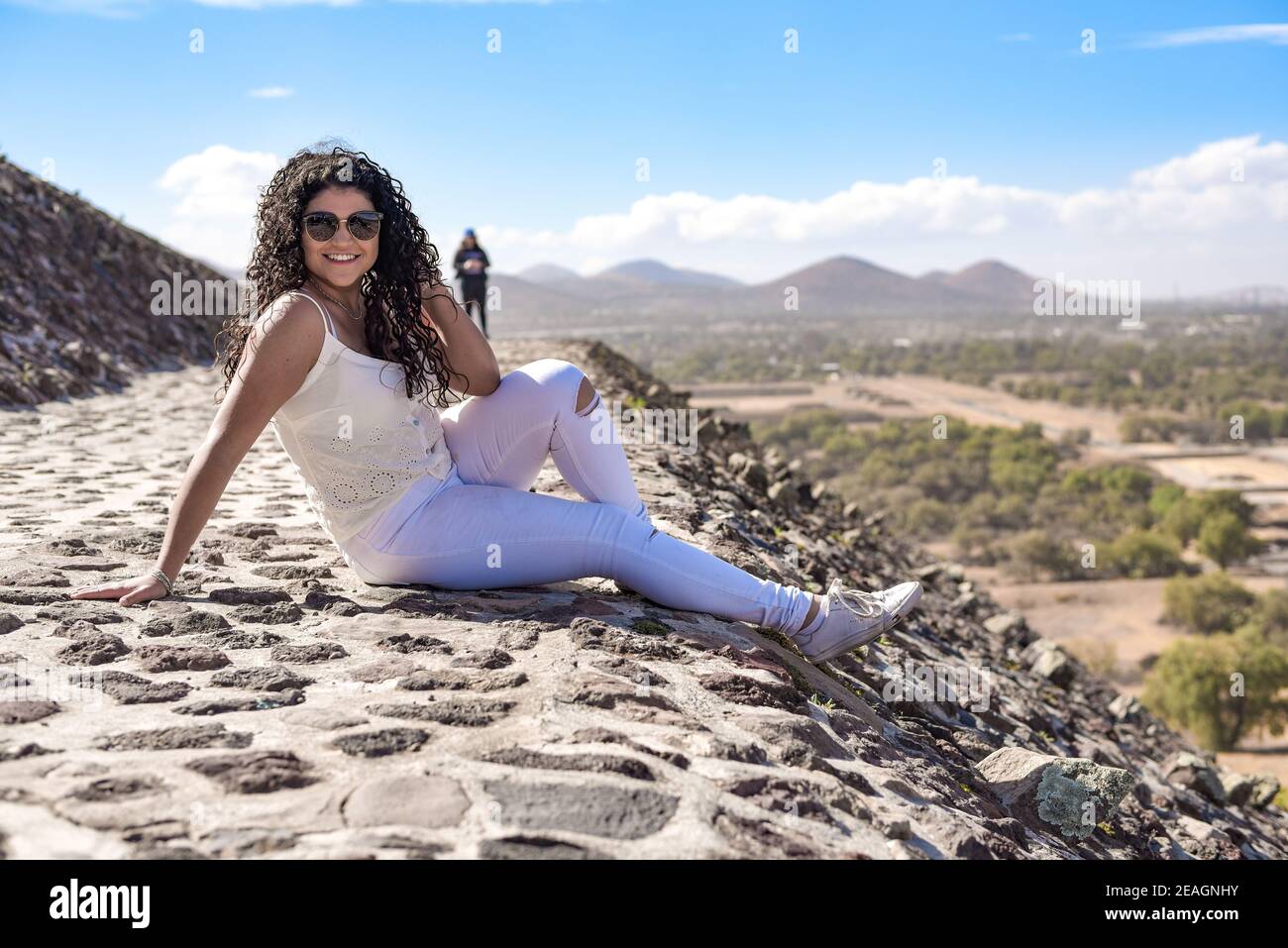 Smiling Hispanic female sitting on a pyramid in Teotihuacan Stock Photo ...