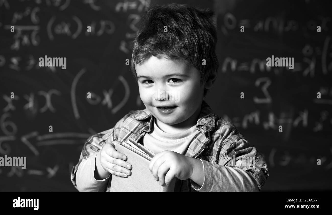 Smart child on smiling face, holds book in hands. Pupil, preschooler on ...