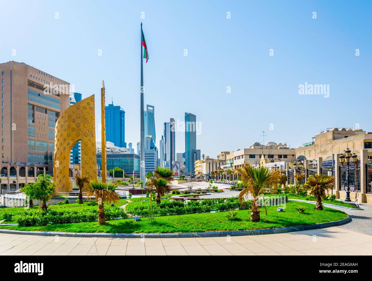 View of a a golden monument with a small park in the central Kuwait ...