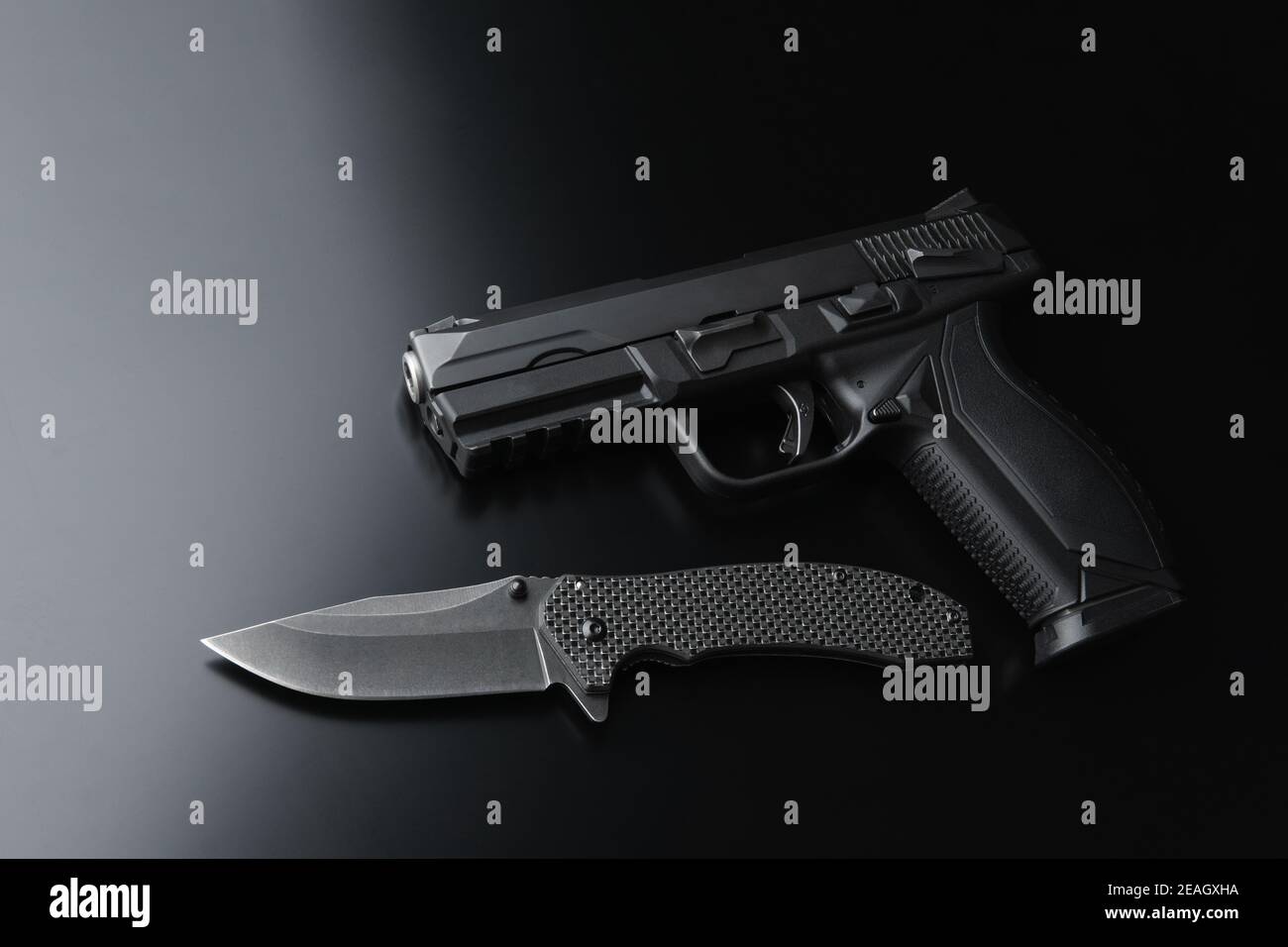 Black modern pistol and knife on a dark background. A short-barreled ...