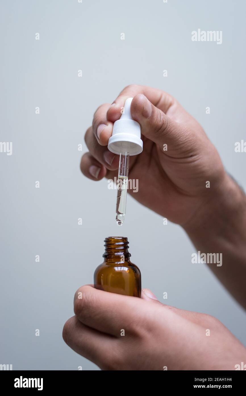 White hands using a dark glass dropper with a white background Stock ...